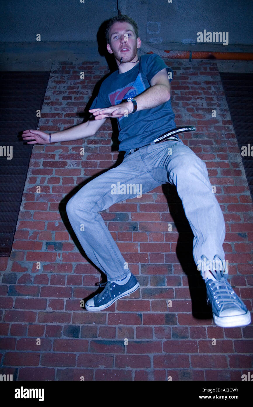 young male man teenager kicking flying in air against brick wall ...