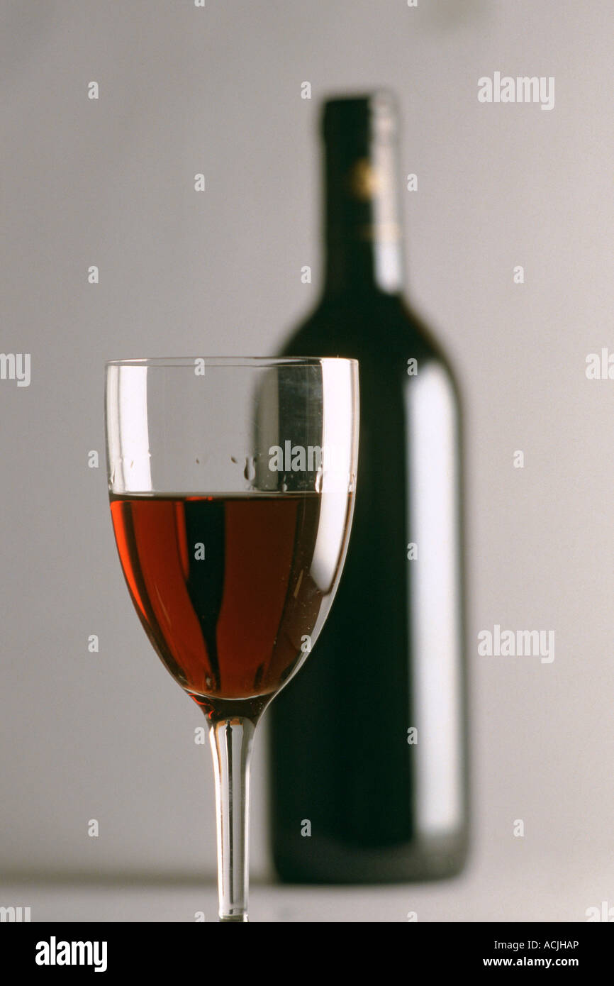 Glass of red wine in front of bottle grey background Stock Photo - Alamy