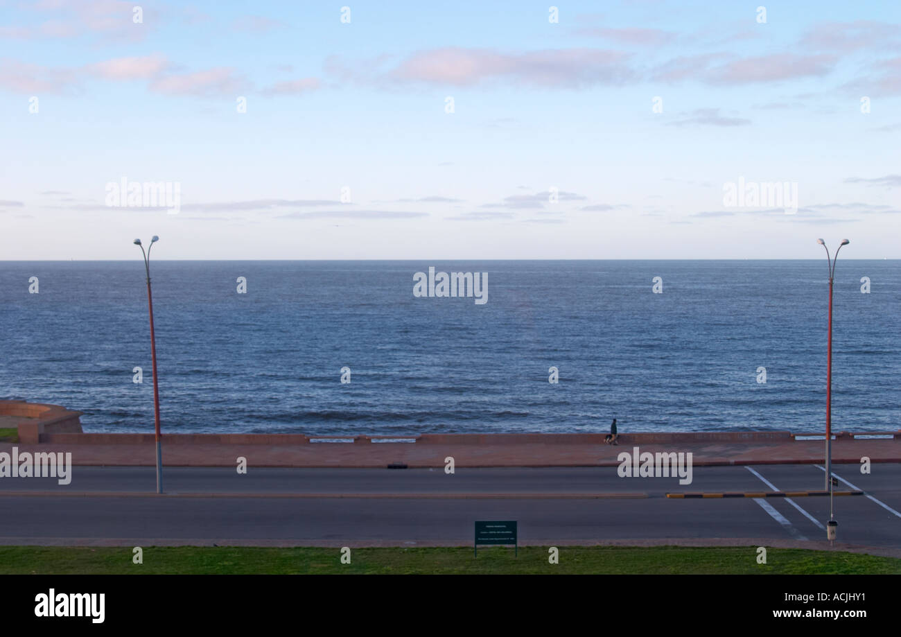 Coast line at dawn with horizon a man walking the dog, two lamp posts ...