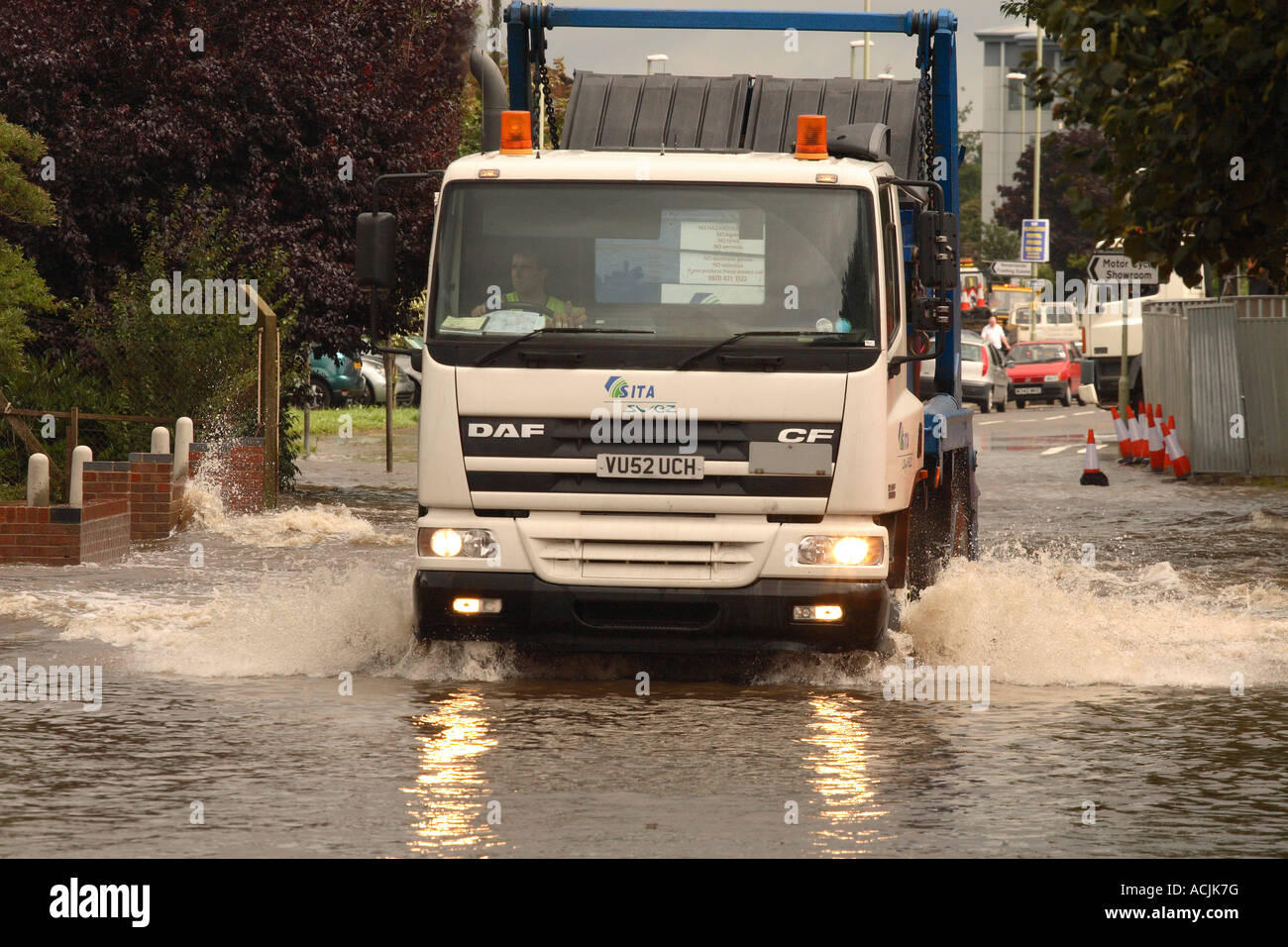 Skip lorry driving through rain flooded road in Gloucester summer 2007 ...