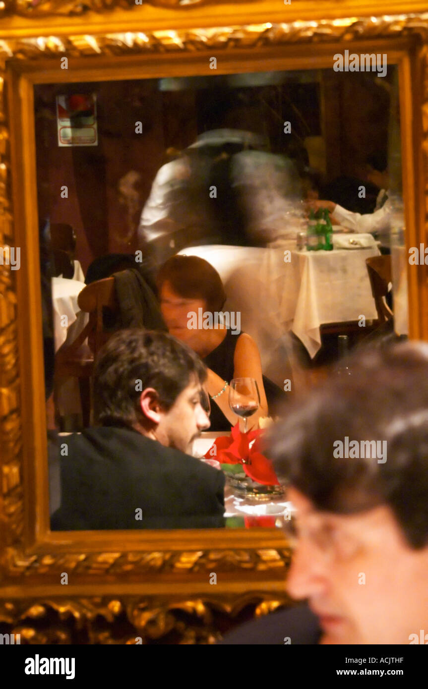 Mirror reflection of guests at the dining table, mirror in heavy ...