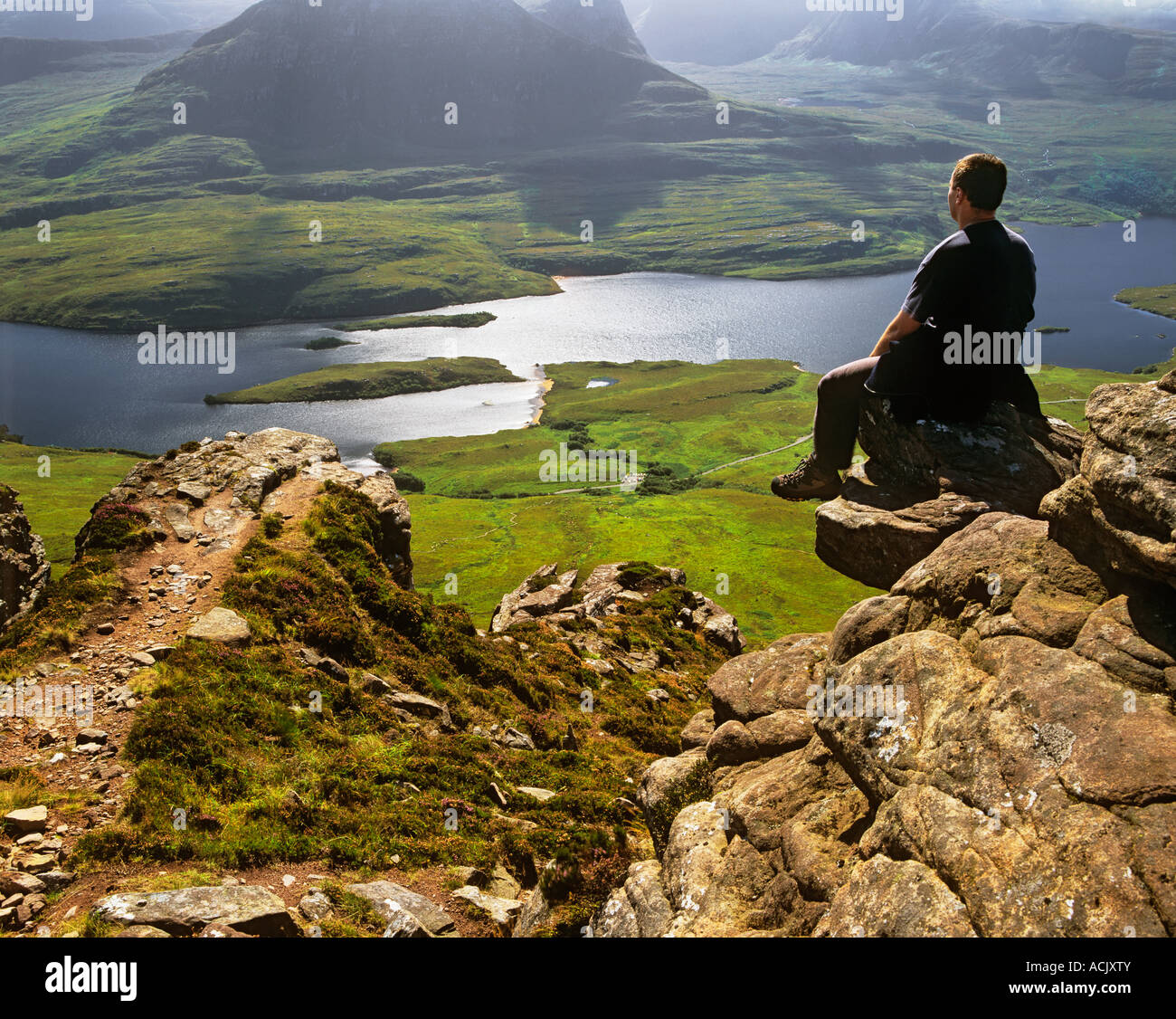 A hill walker admiring the view from the summit ridge of Stac Pollaidh ...