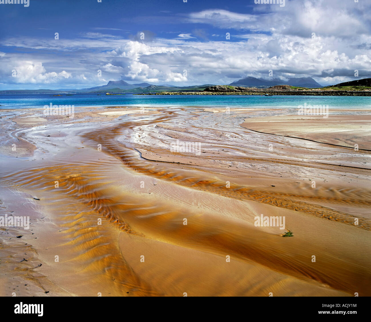A tanin stained peat stream meanders along the red sand beach toward ...
