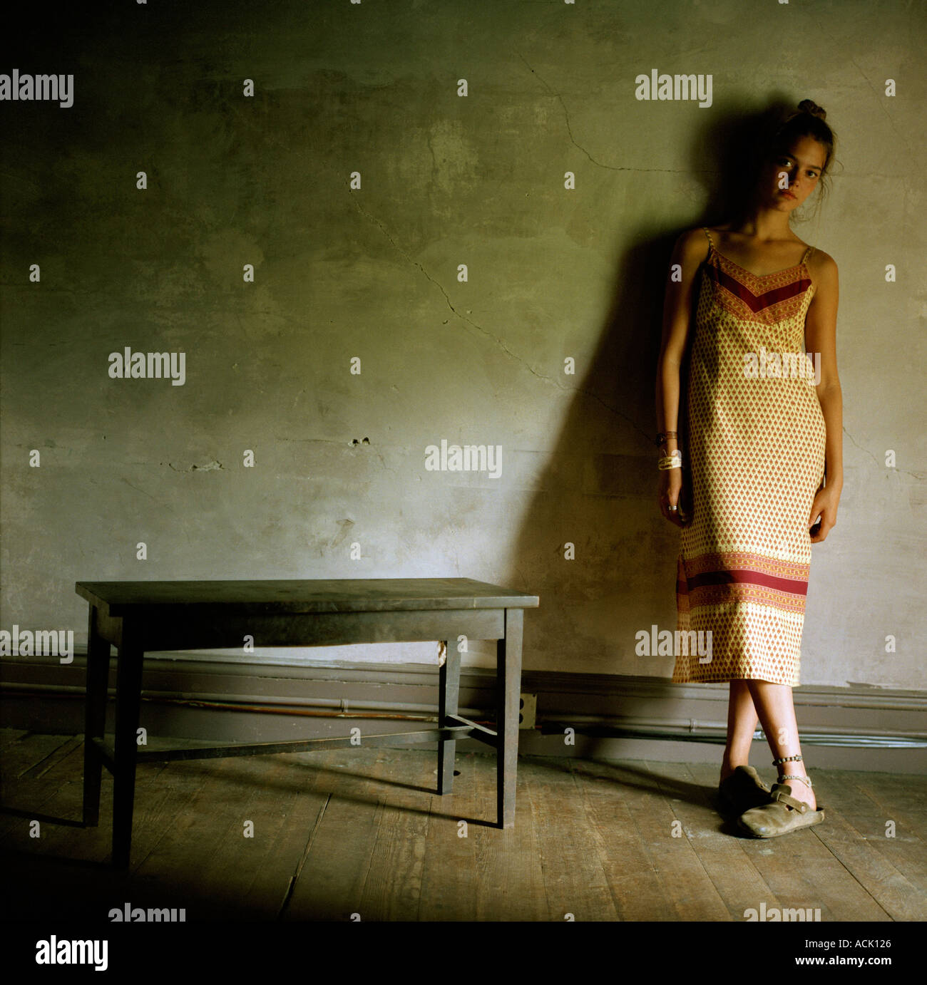 A young woman stands with her legs crossed by a small bench Stock Photo ...