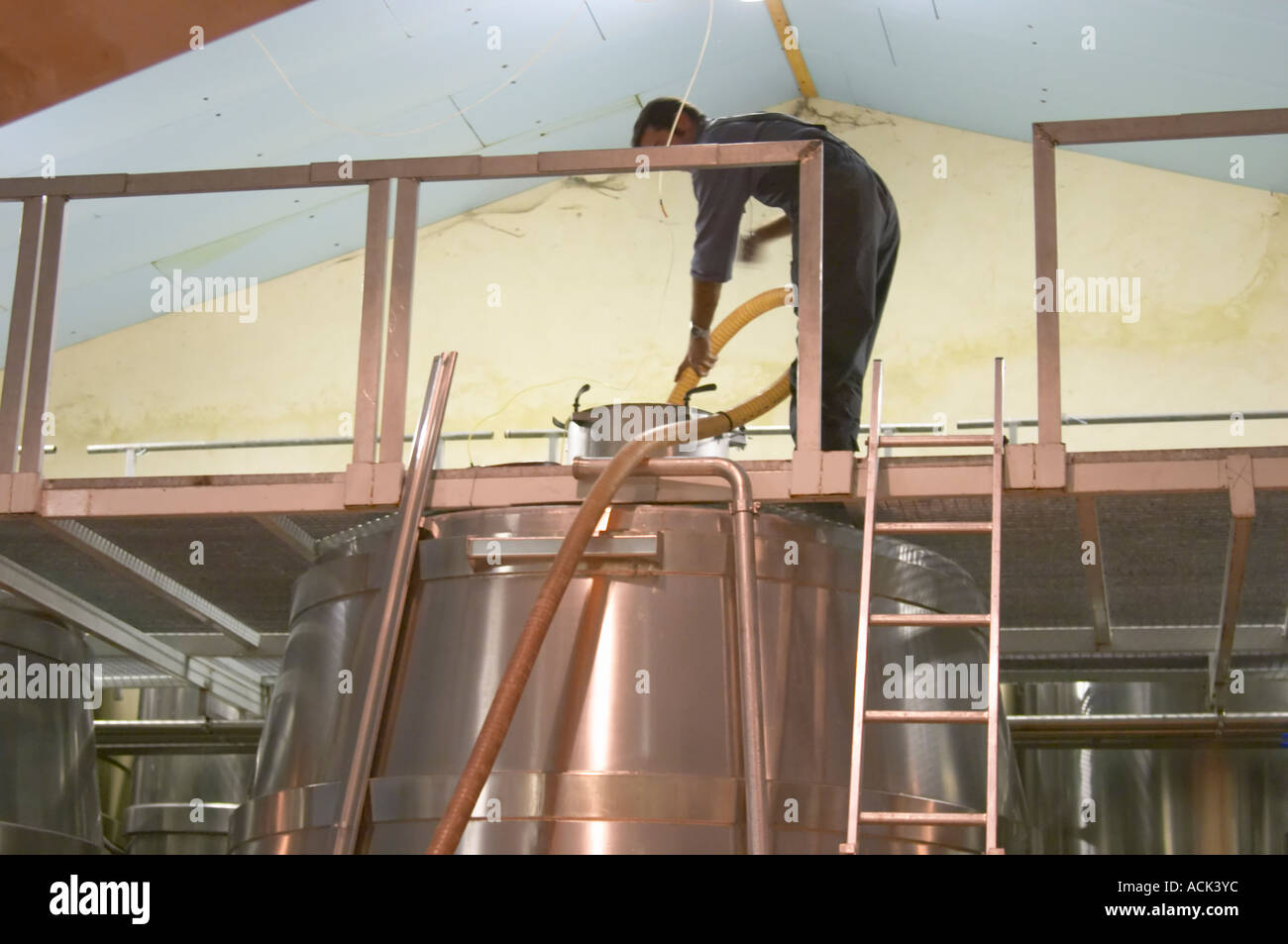 A winery worker pumping over the red wine in a stainless steel ...