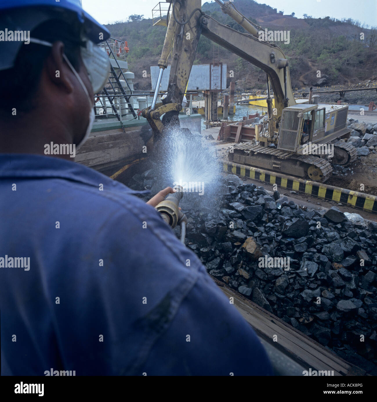 Spraying water over quarried rock which is being loaded onto stone ...
