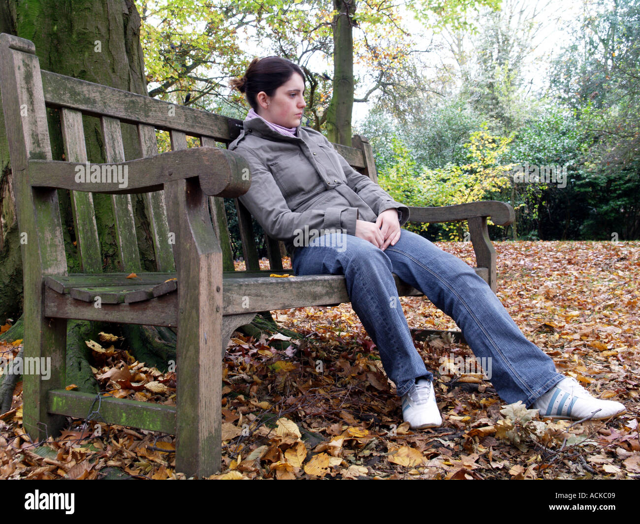 Young woman sat on park bench Stock Photo - Alamy