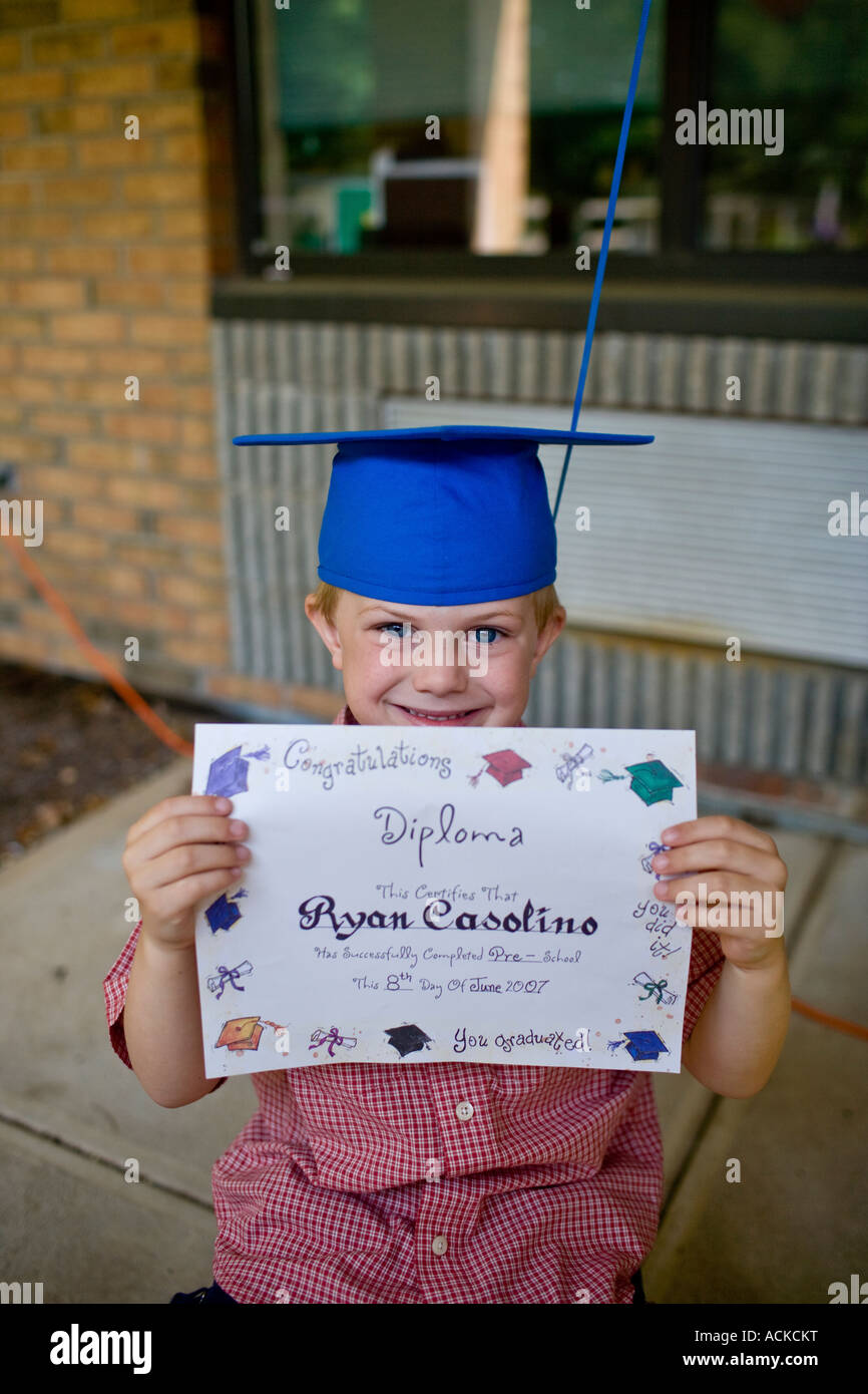 A small boy shows his diploma at a pre-school daycare graduation ...