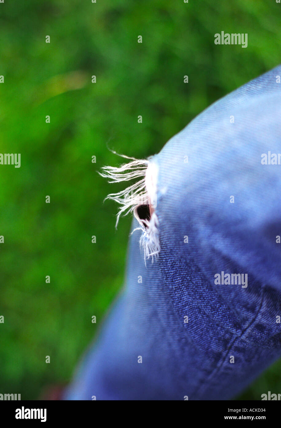 saturated image of jeans with rip in knee lawn backround Stock Photo ...