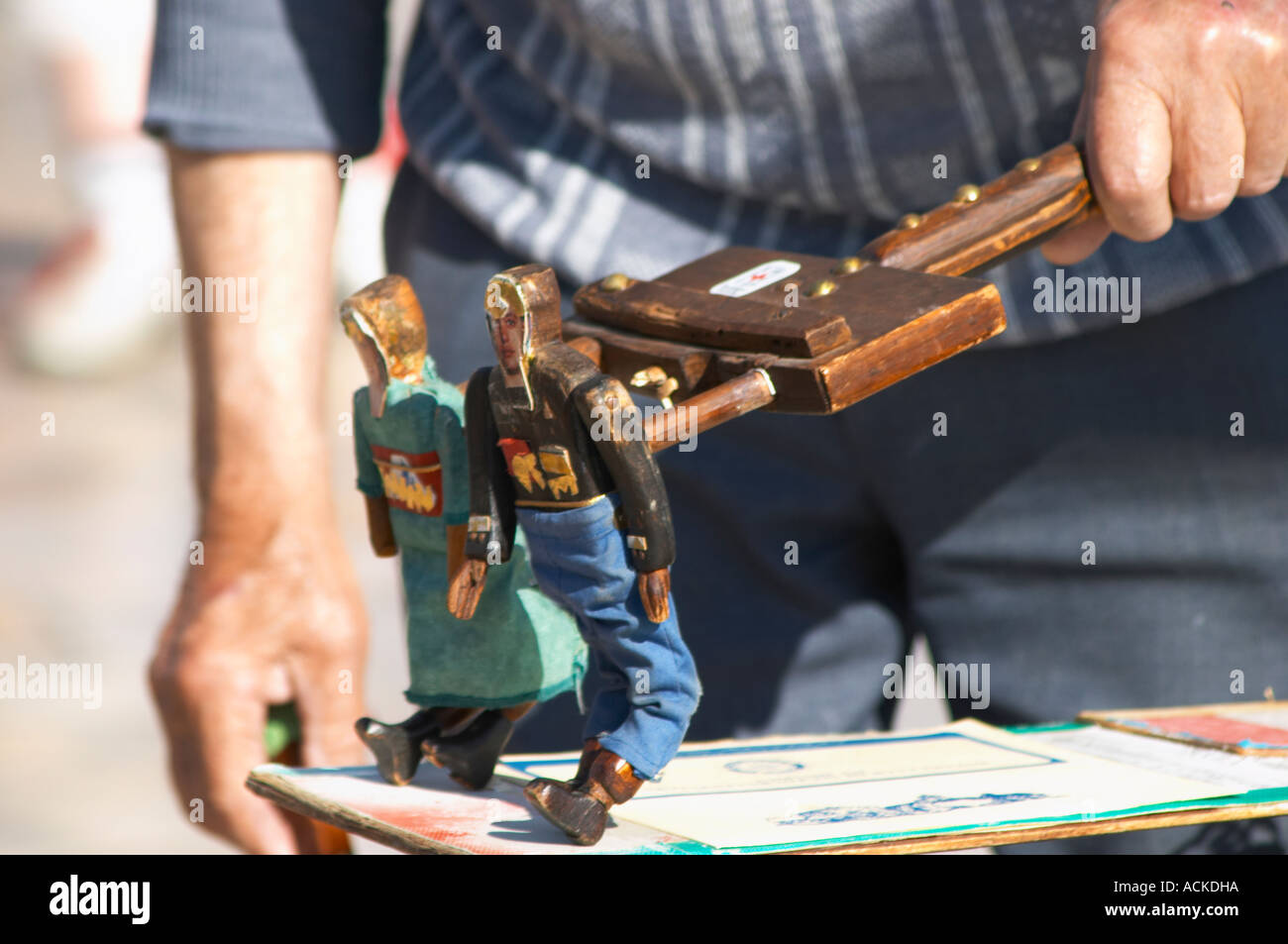 A street entertainer, old man showing to children two carved wooden ...