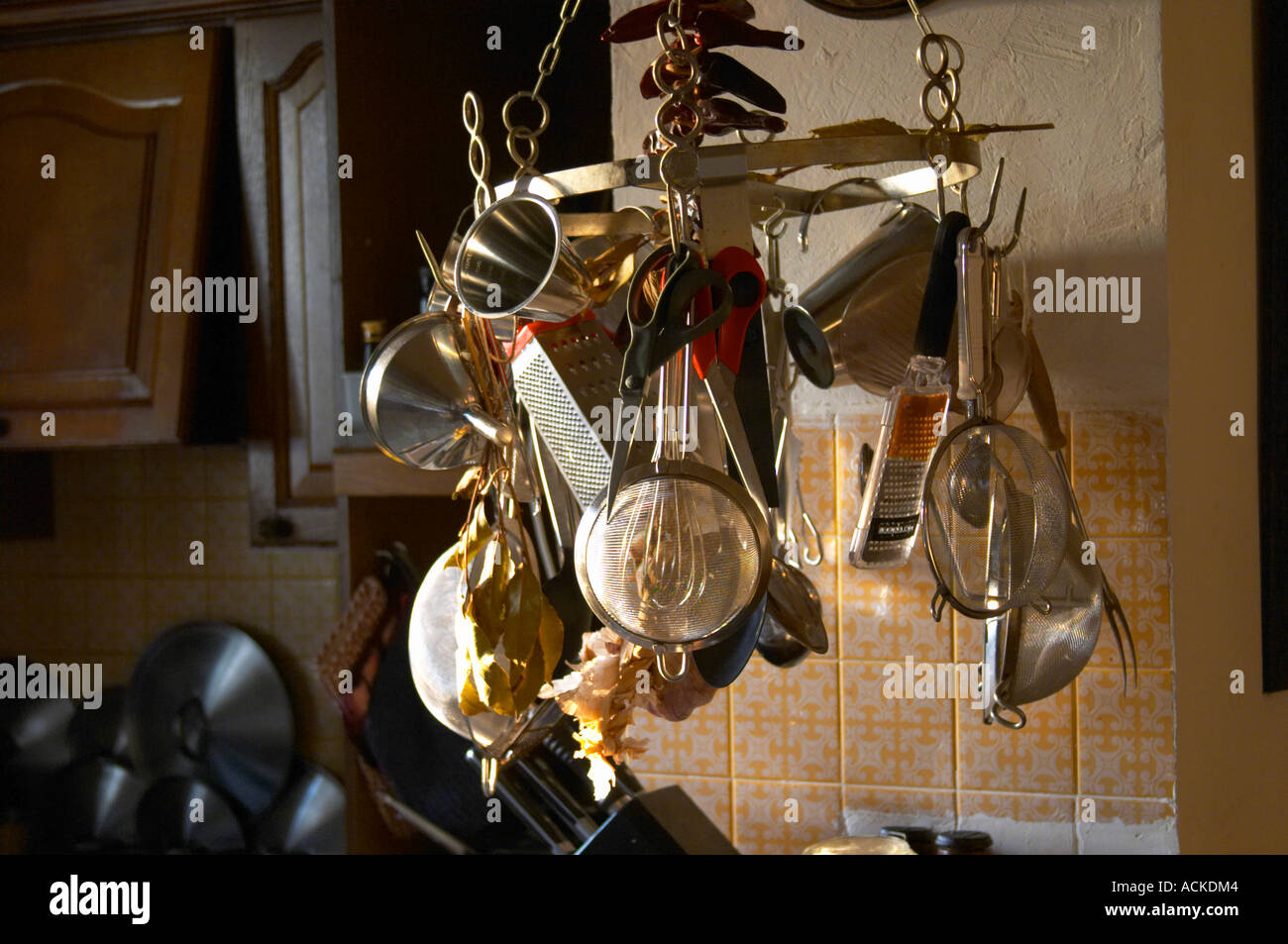 Kitchen utensils in stainless steel hanging on hooks in the Provence ...