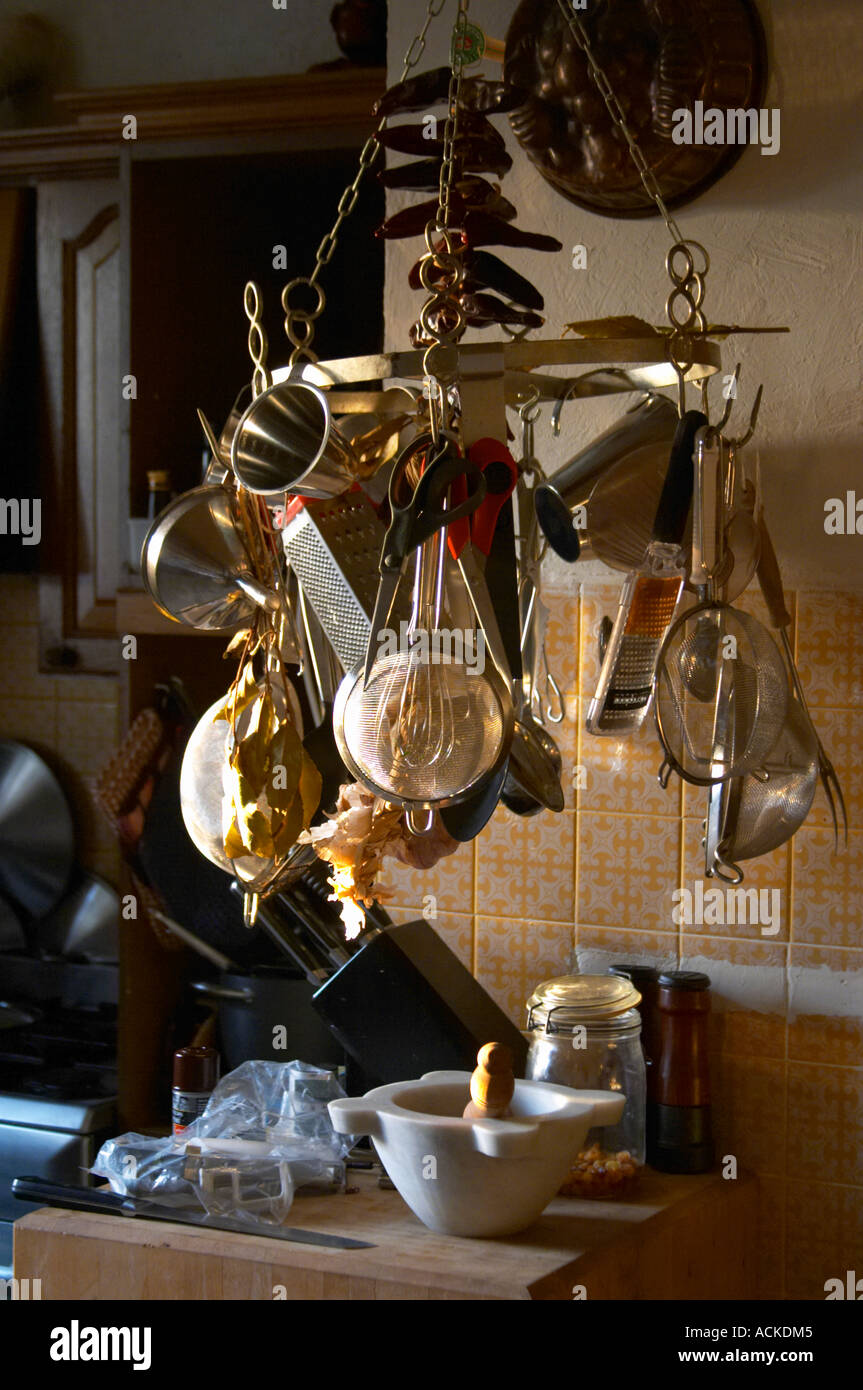 Kitchen utensils in stainless steel hanging on hooks in the Provence ...