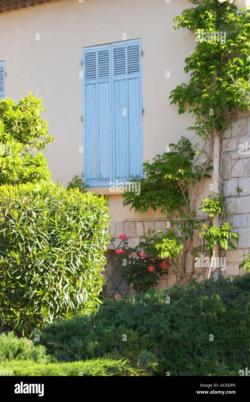 In a Provencal garden: a house with wooden window shutters painted pale ...