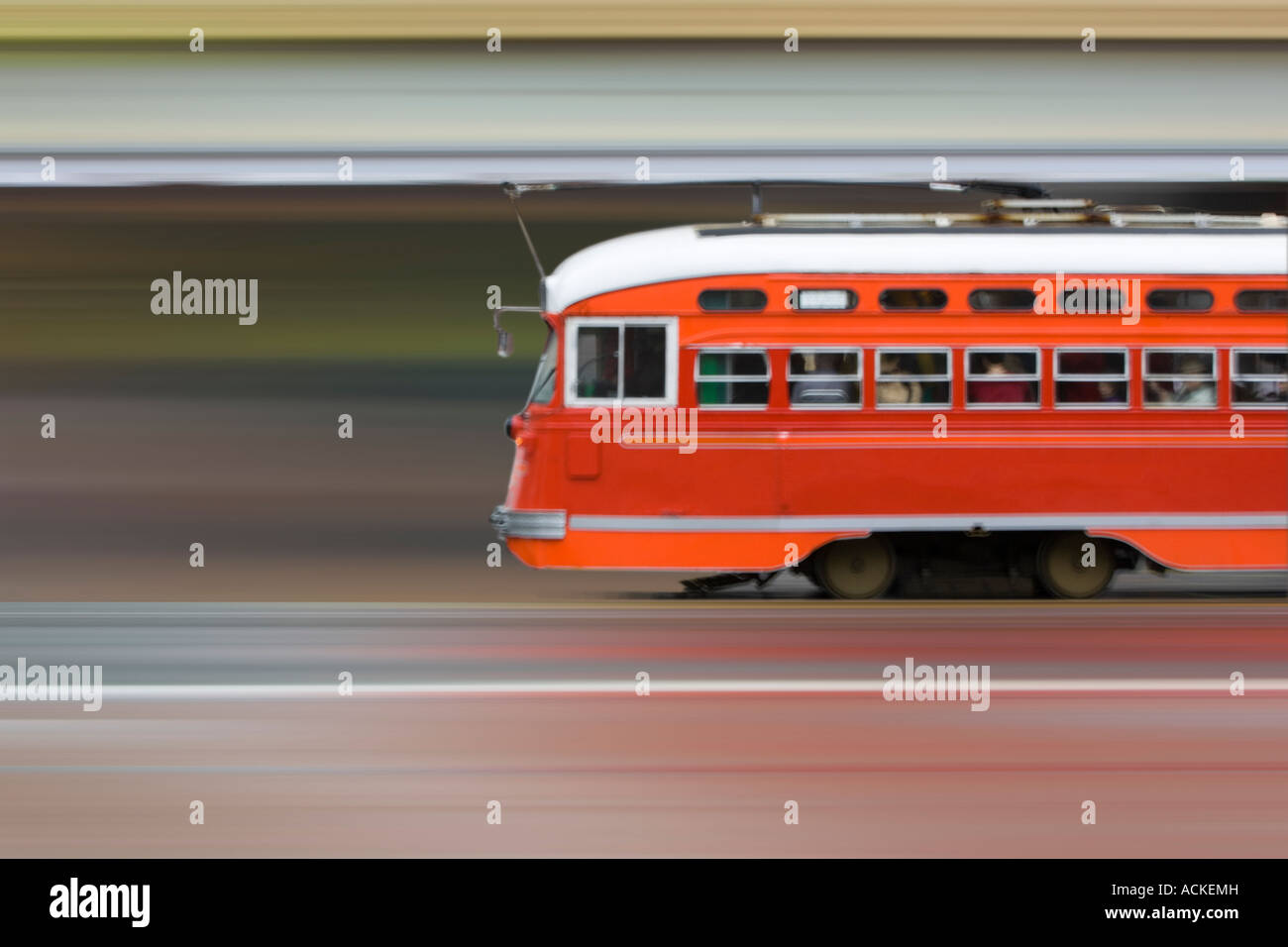 a red passenger bus is moving fast on the rail against blurred ...