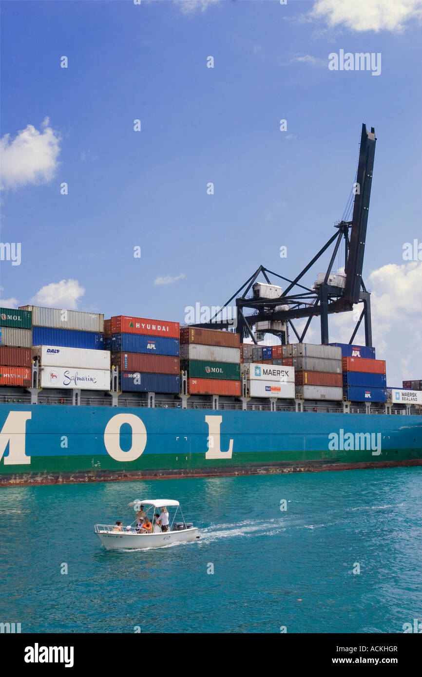 Small pleasure boat driving by a container ship loaded with cargo ...