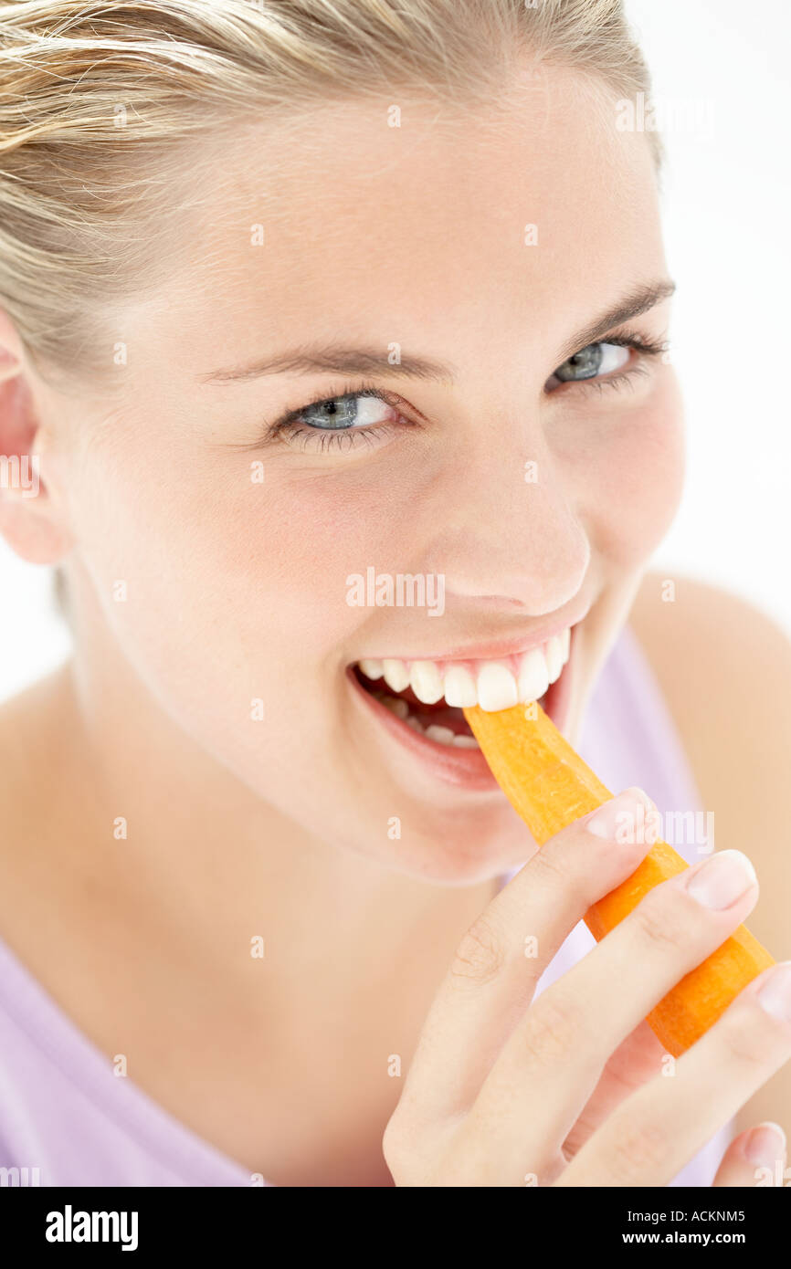A young woman biting a carrot Stock Photo - Alamy