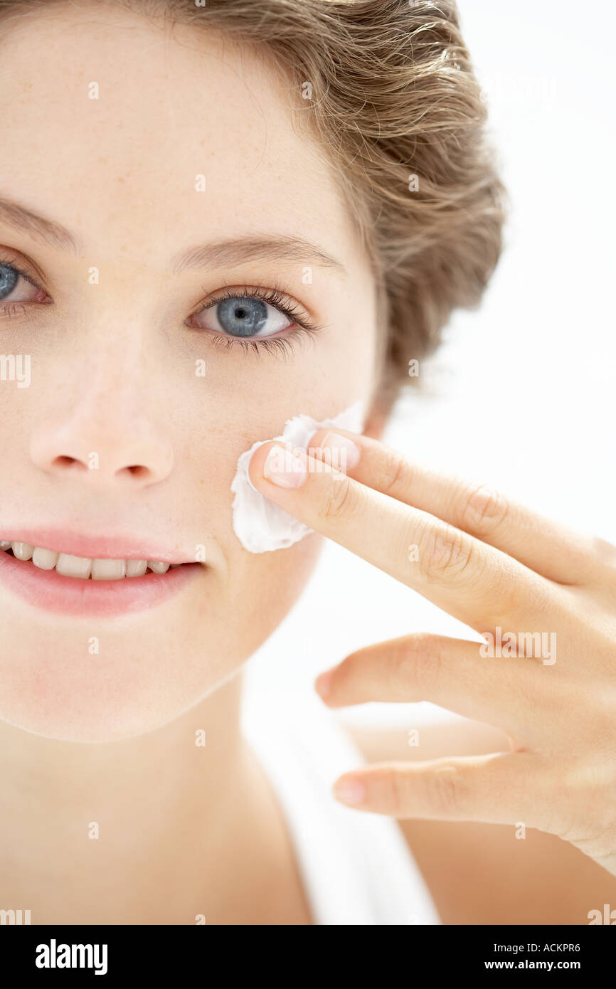 Young woman applying cream on face Stock Photo - Alamy