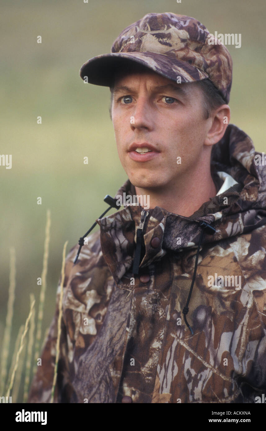 Portrait of a male hunter wearing camoflauge sitting in a tall grass ...