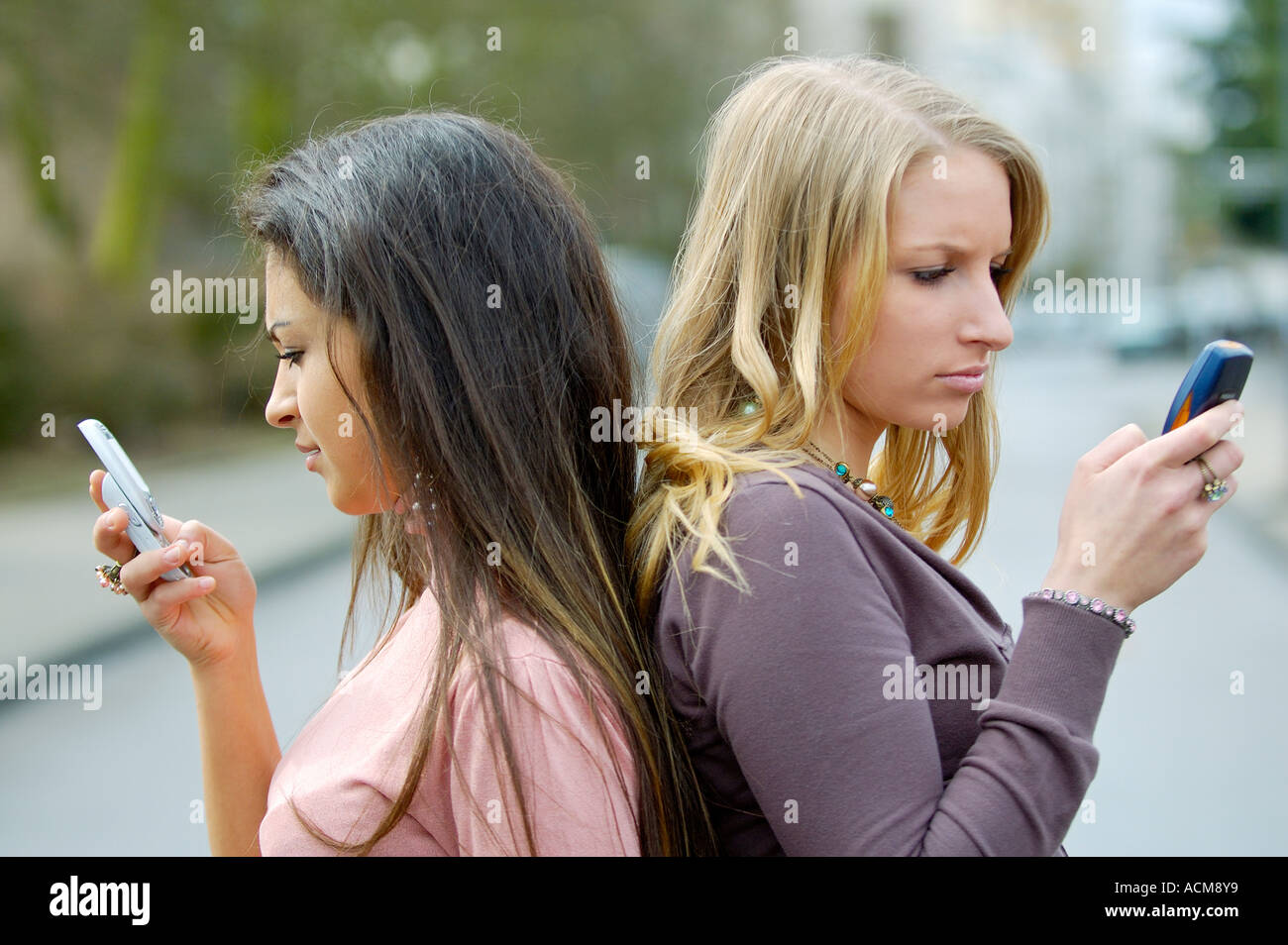 two teenage girls texting on mobile phones Stock Photo - Alamy