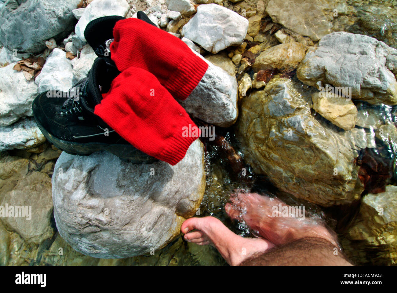cooling the feet in cold water by hiking through stony terrain in the ...