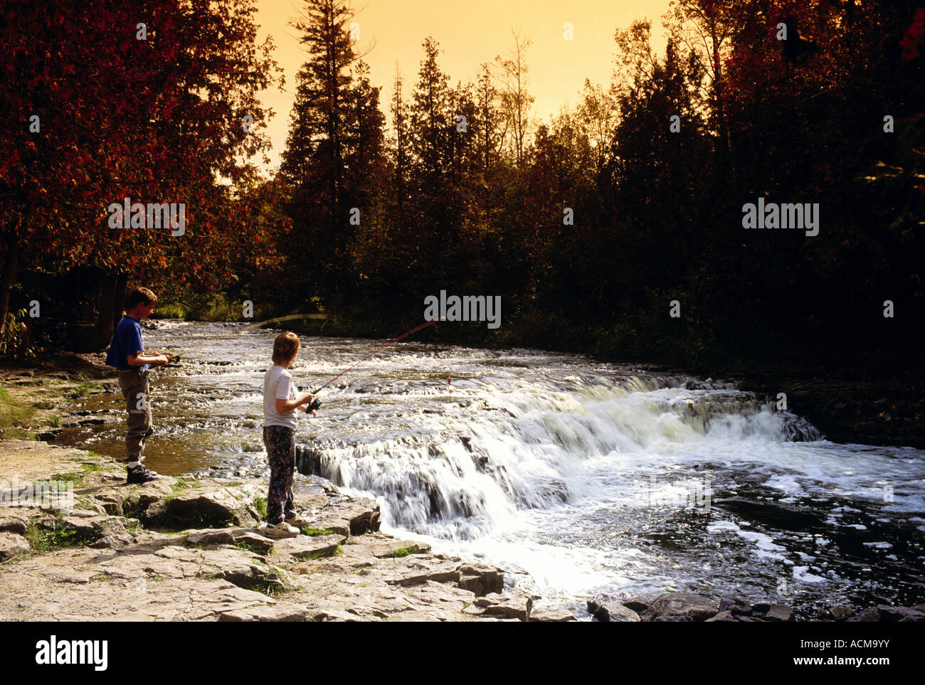 Boys fishing in autumn at Ocqueoc Falls, largest in lower peninsula of ...