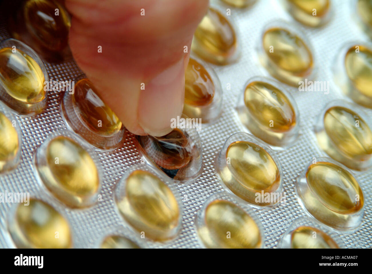 finger pushing a capsule out of a packing with many similar capsules ...