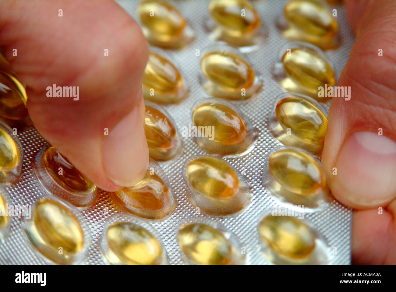 finger pushing a capsule out of a packing with many similar capsules ...