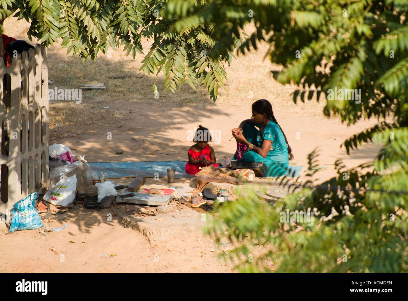 A LABORER WOMAN IS TAKING REST UNDER THE SHADE OF A TREE ALONG WITH HER ...