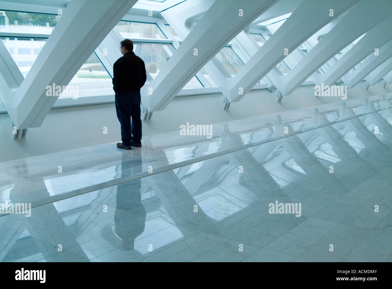 A MAN IS LOOKING OUT OF A BIG WINDOW FROM INSIDE OF A WHITE REFLECTIVE ...