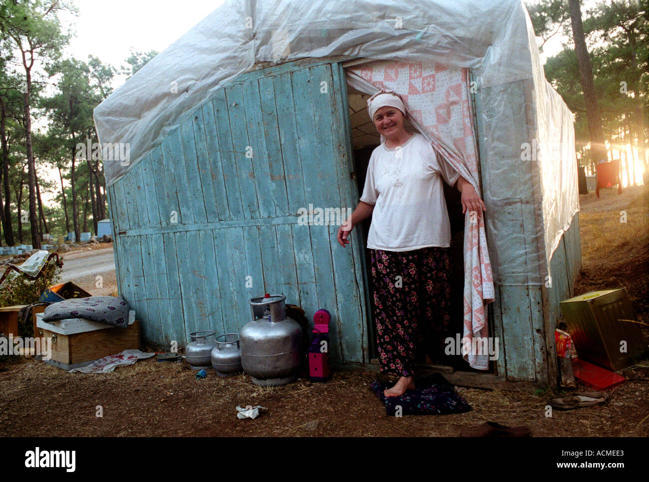 Female migrant bee keeper next to her temporary home preparing food for ...