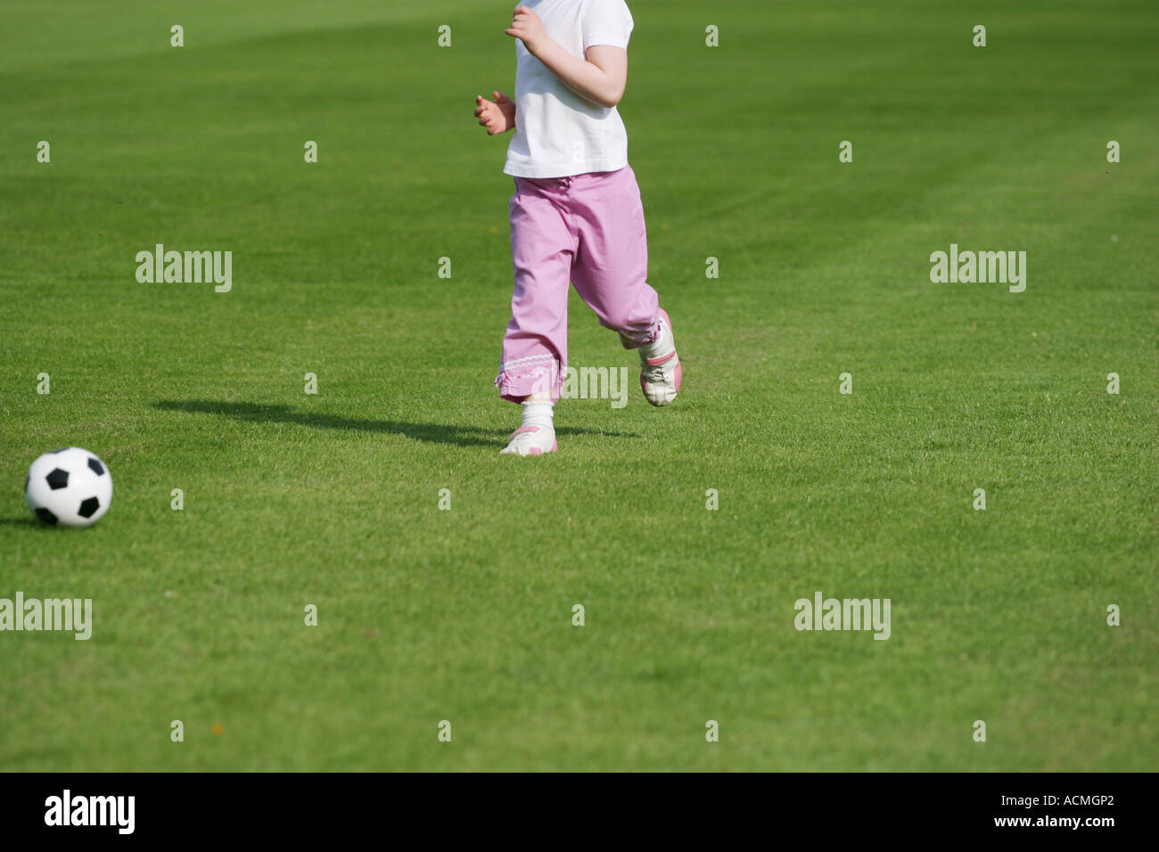 Young girl running around park playing football in the summer sun Stock ...