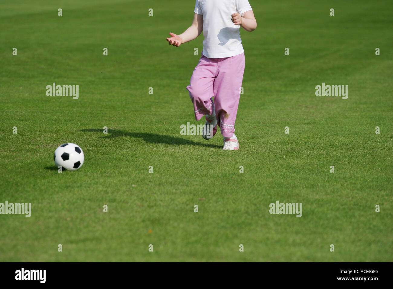 Young girl running around park playing football in the summer sun Stock ...