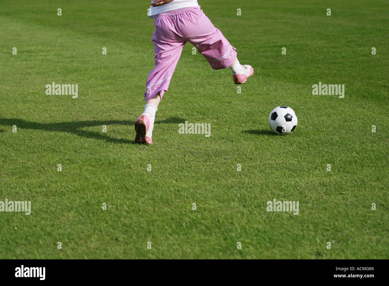 Young girl running around park playing football in the summer sun Stock ...