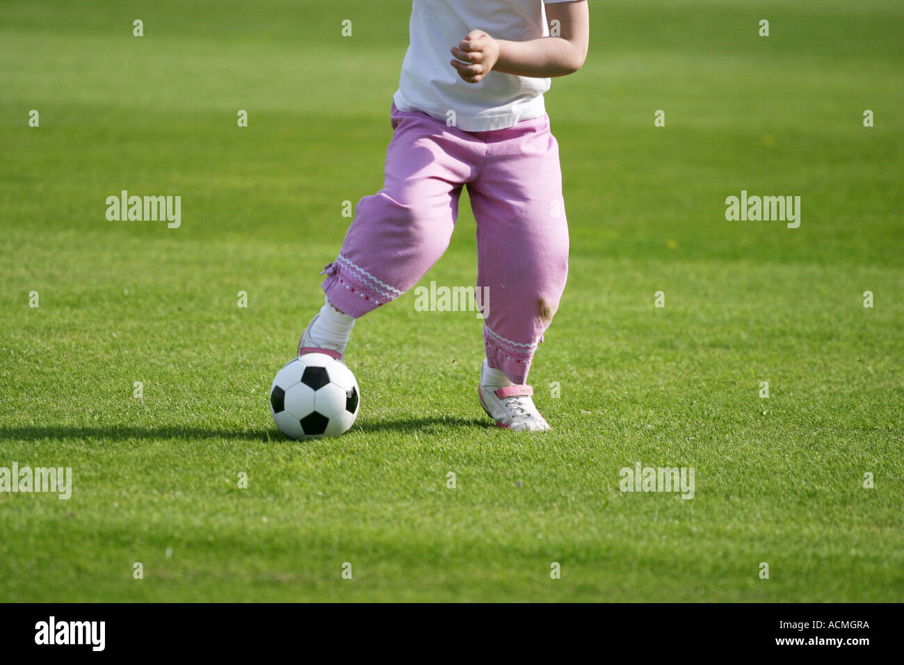 Young girl running around park playing football in the summer sun Stock ...