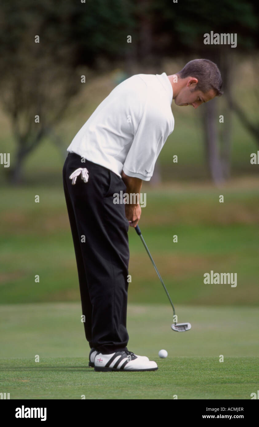 A young golfer putts for birdie at an english golf course in the late ...
