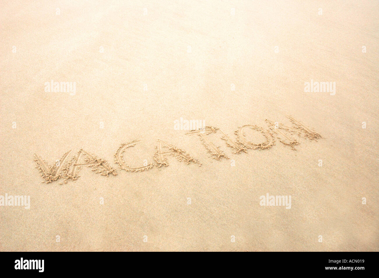 Word vacation written in sand on beach Stock Photo - Alamy