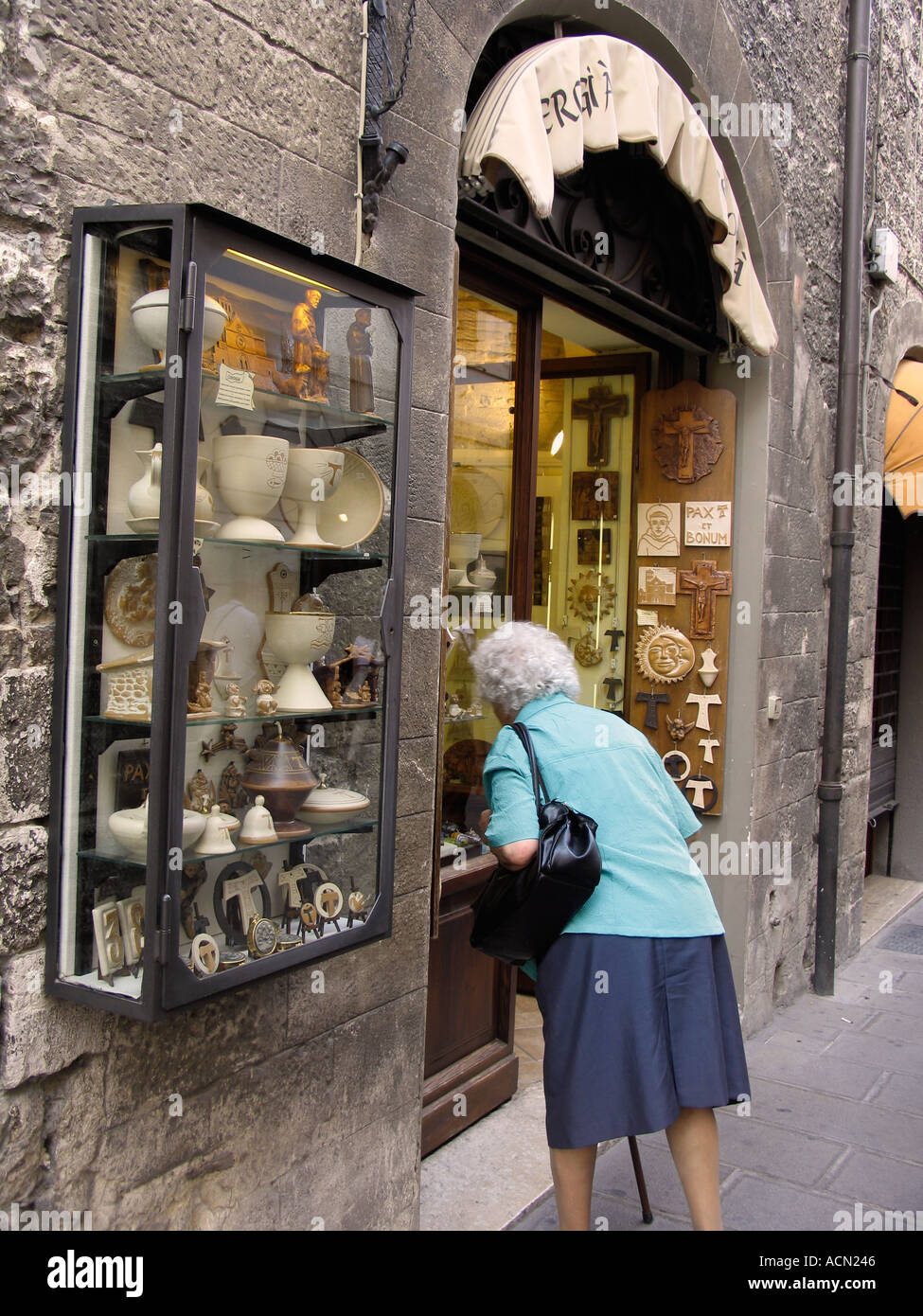 Older woman looking into window of store selling religious merchandise ...