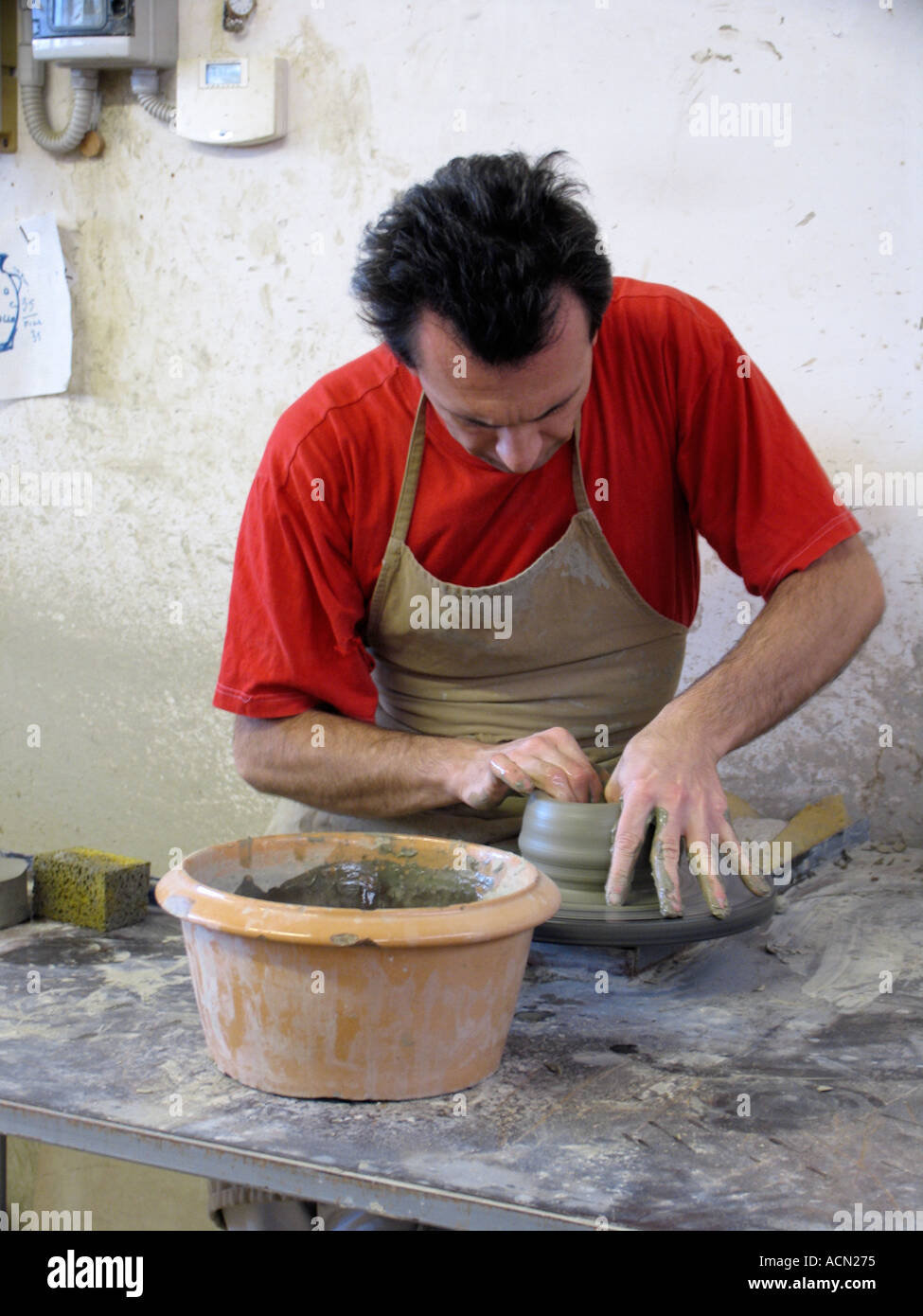Man forming clay on a potters wheel at a ceramics factory in Deruta ...
