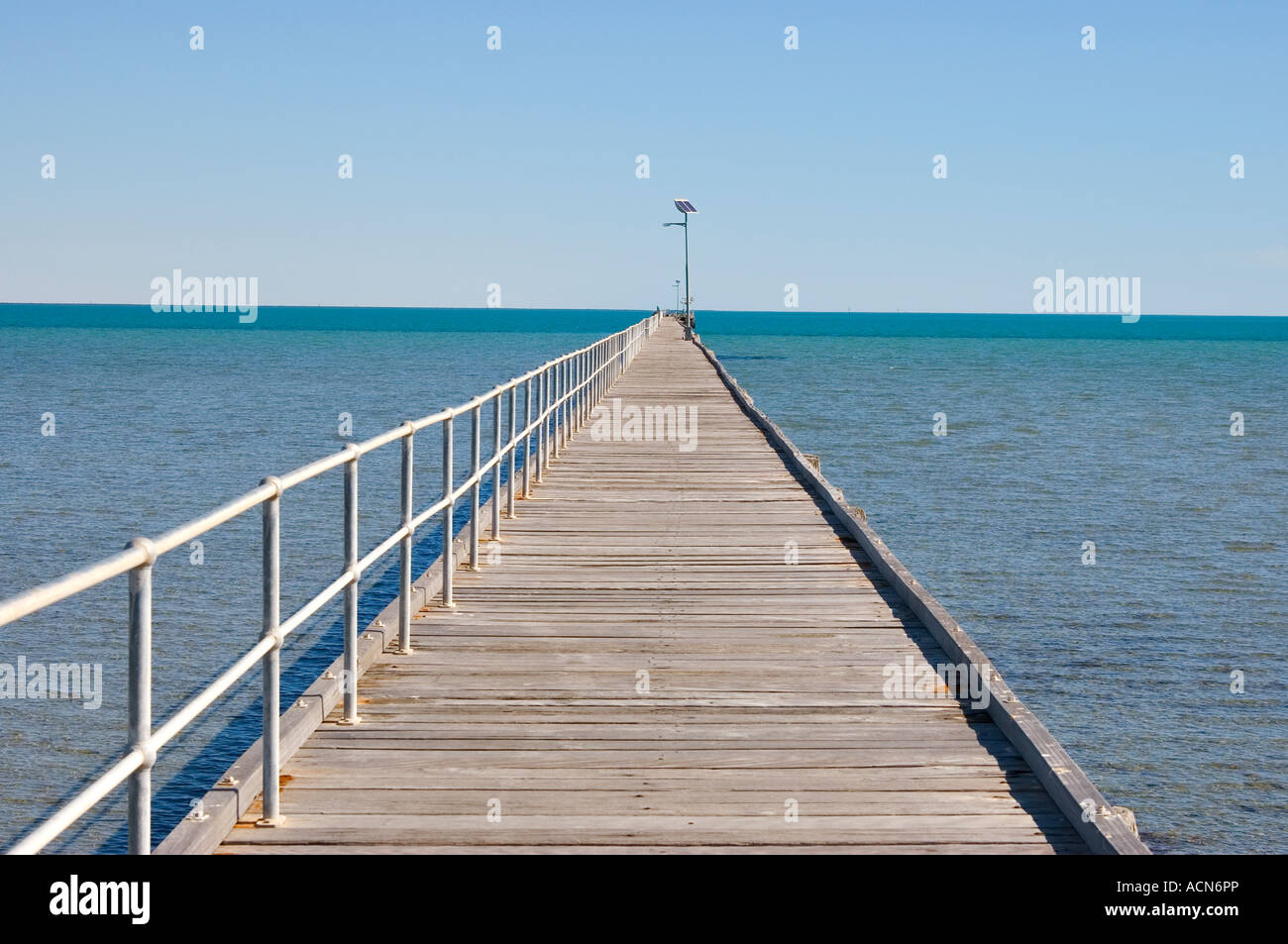 the long jetty reaches far out into the blue sea Stock Photo - Alamy