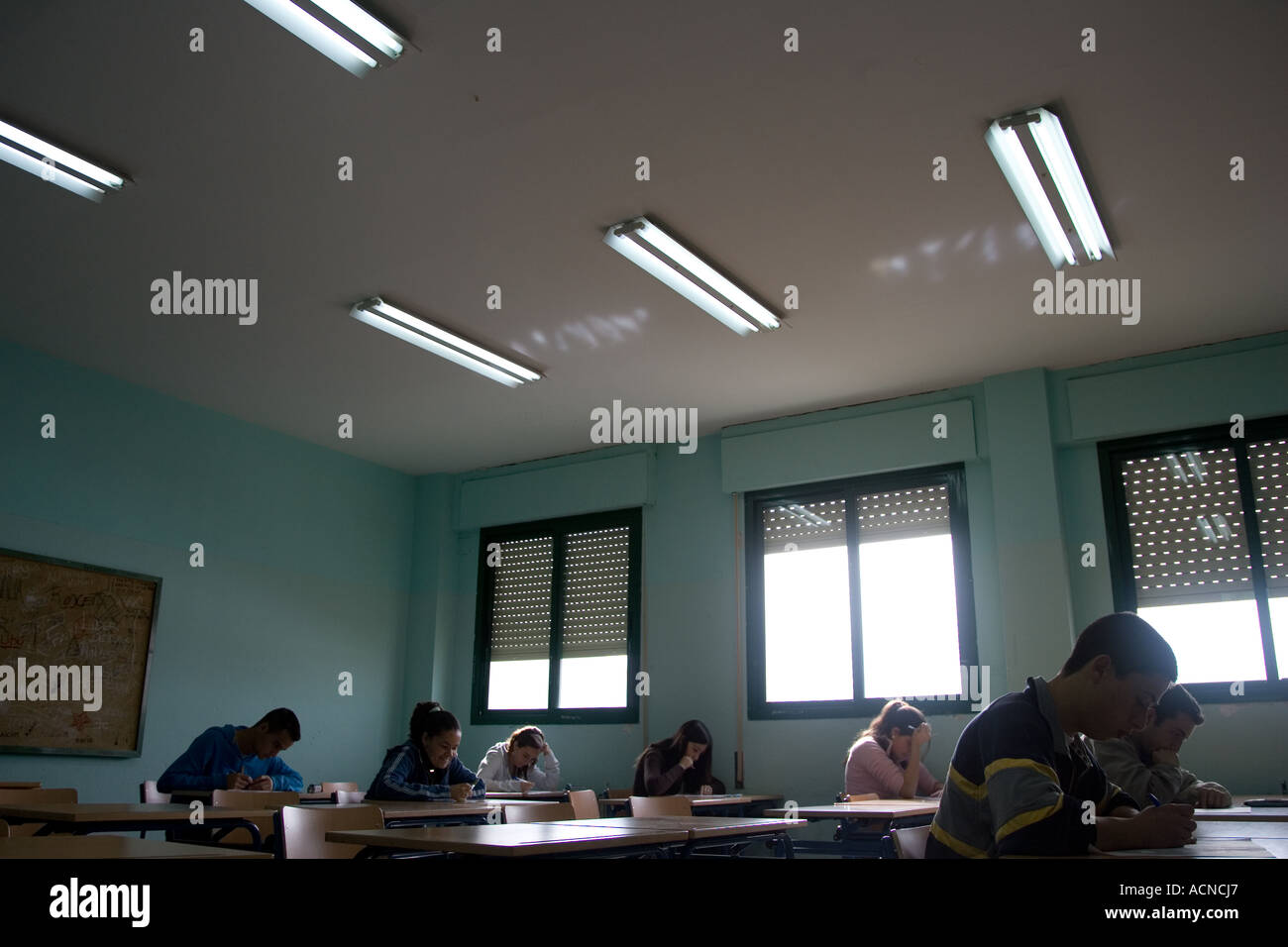 Low angle, backlighted view of students taking an examination in their ...