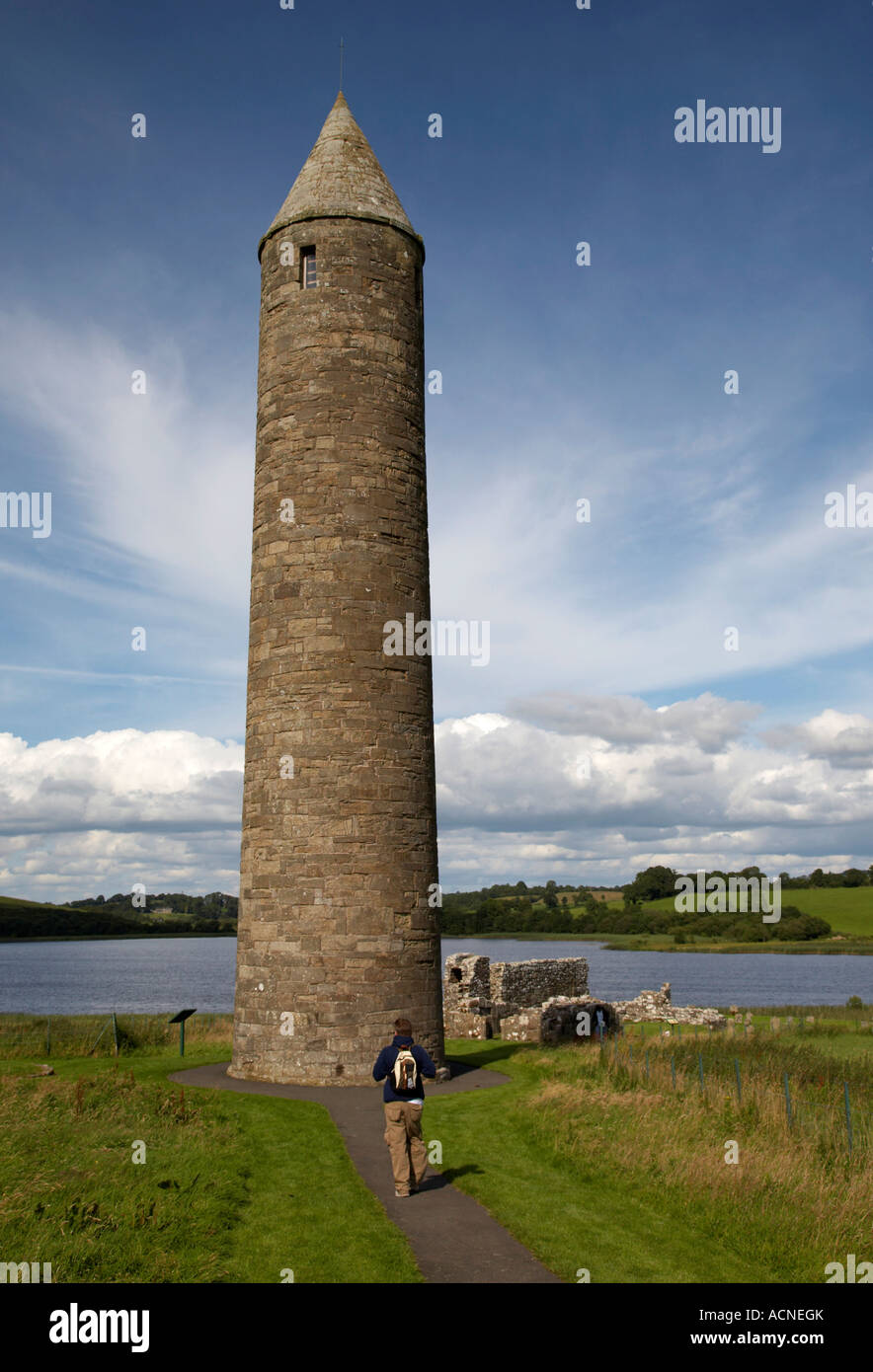 tourist walking down towards the 12th century round tower on devenish ...
