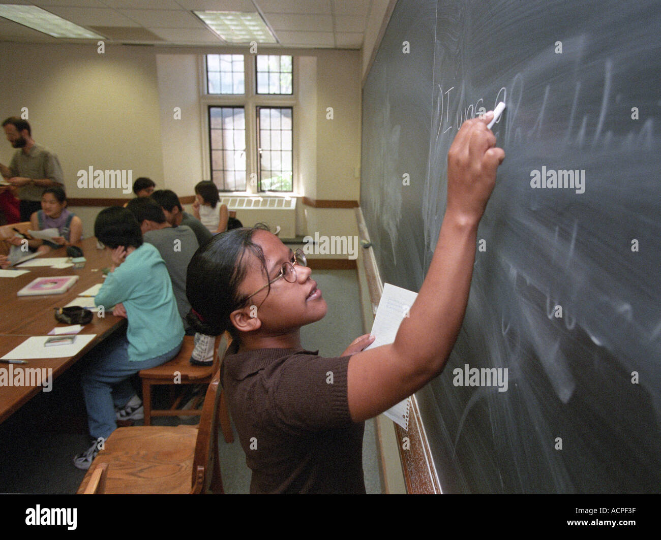 Young teacher writing on blackboard in school classroom Stock Photo - Alamy