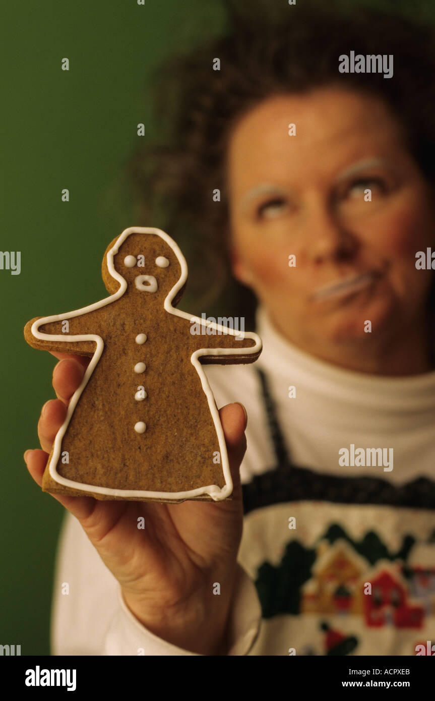 Lady with puzzled look on face holding gingerbread cookie Stock Photo ...