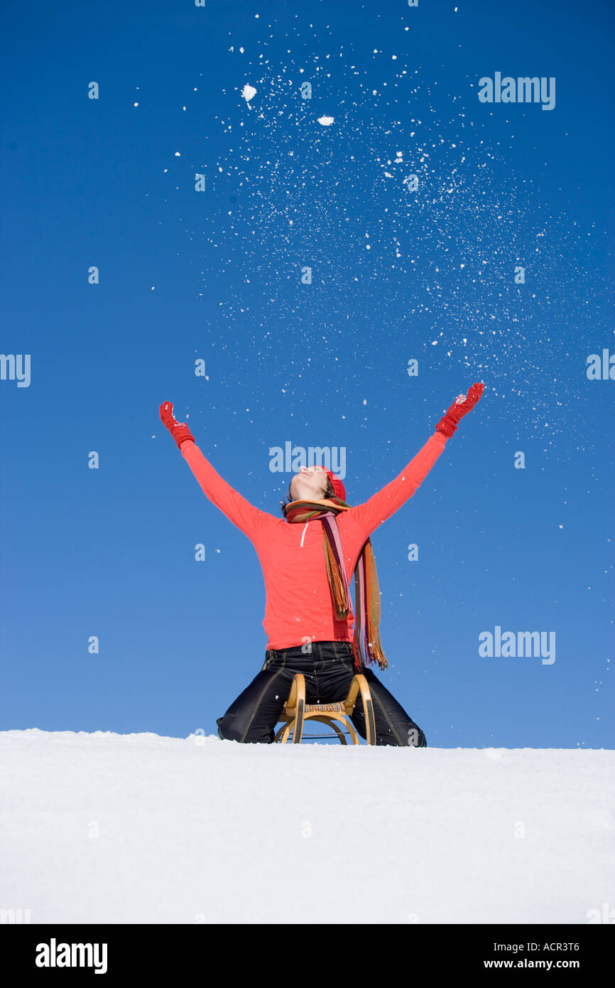 Woman sitting on sledge, lifting arms up Stock Photo - Alamy