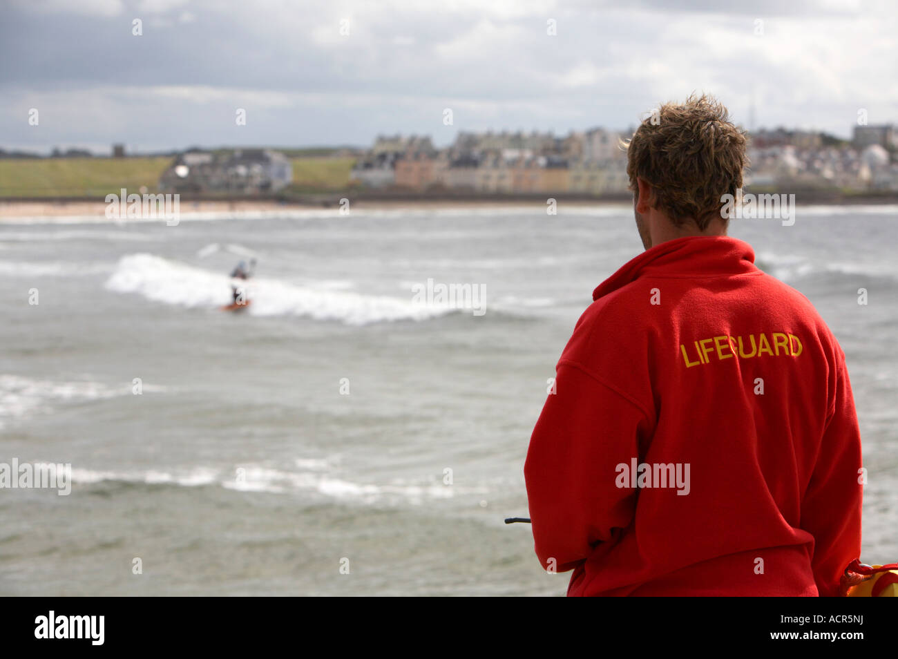 male surf rescue lifeguard watching over the beach and canoeists in the ...