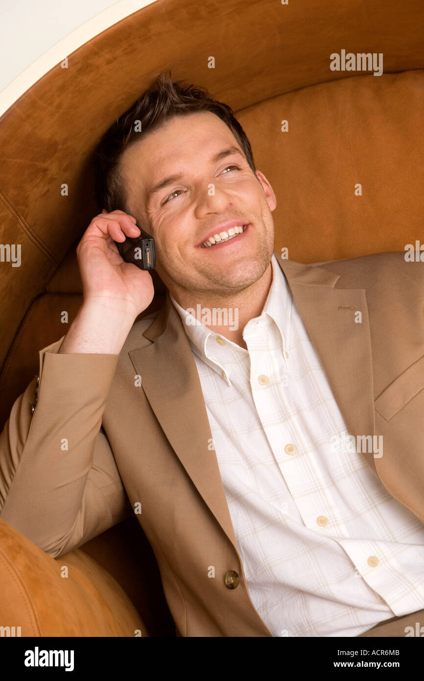 Man sitting on sofa using mobile phone, smiling Stock Photo - Alamy