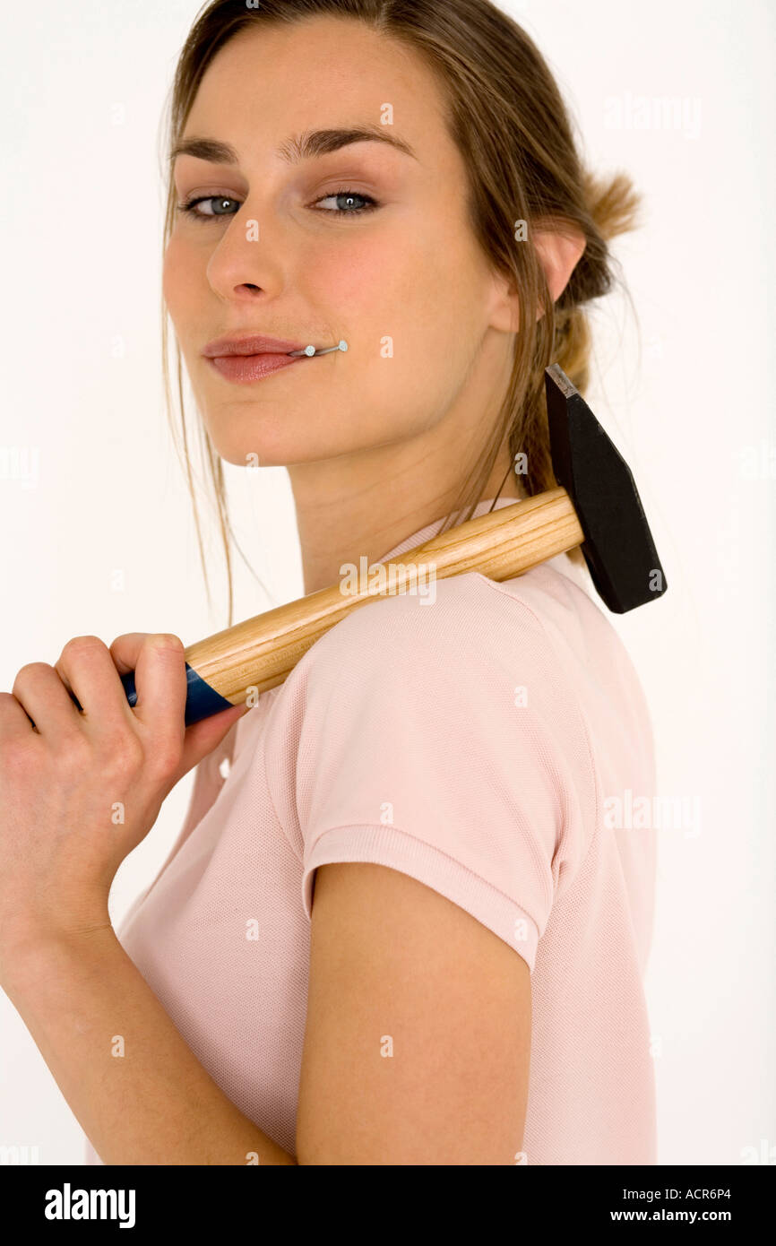 Woman holding hammer with nail in mouth, portrait, close-up Stock Photo ...