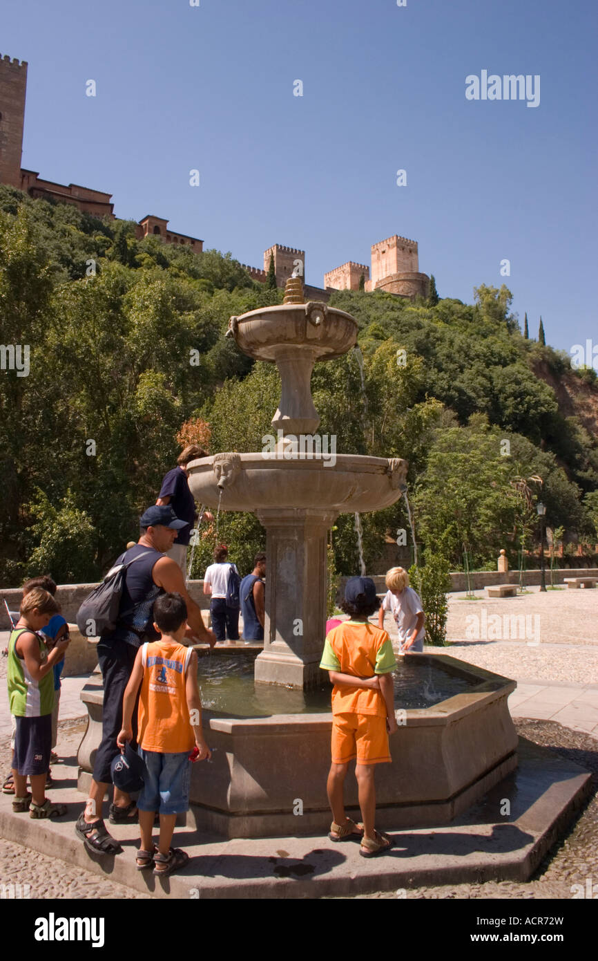 Family beside fountain with Alhambra palace on hill above , Granada ...
