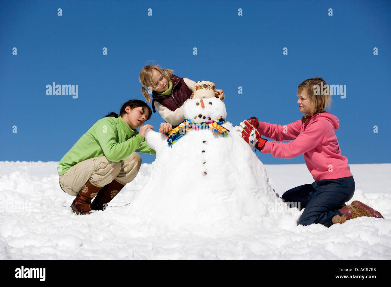 Girls building snowman Stock Photo - Alamy