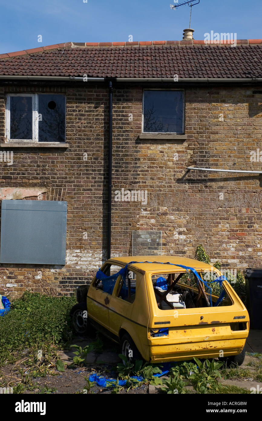 An abandoned yellow car behind a delapidated brick building Stock Photo ...